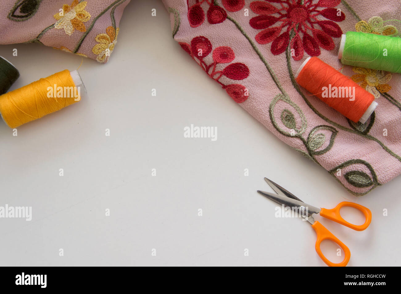 Top view of embroidered cloth and colorful threads on white background ...