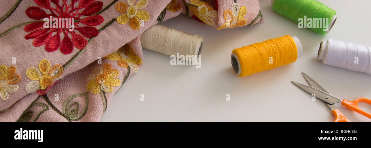 Top view of embroidered cloth and colorful threads on white background ...