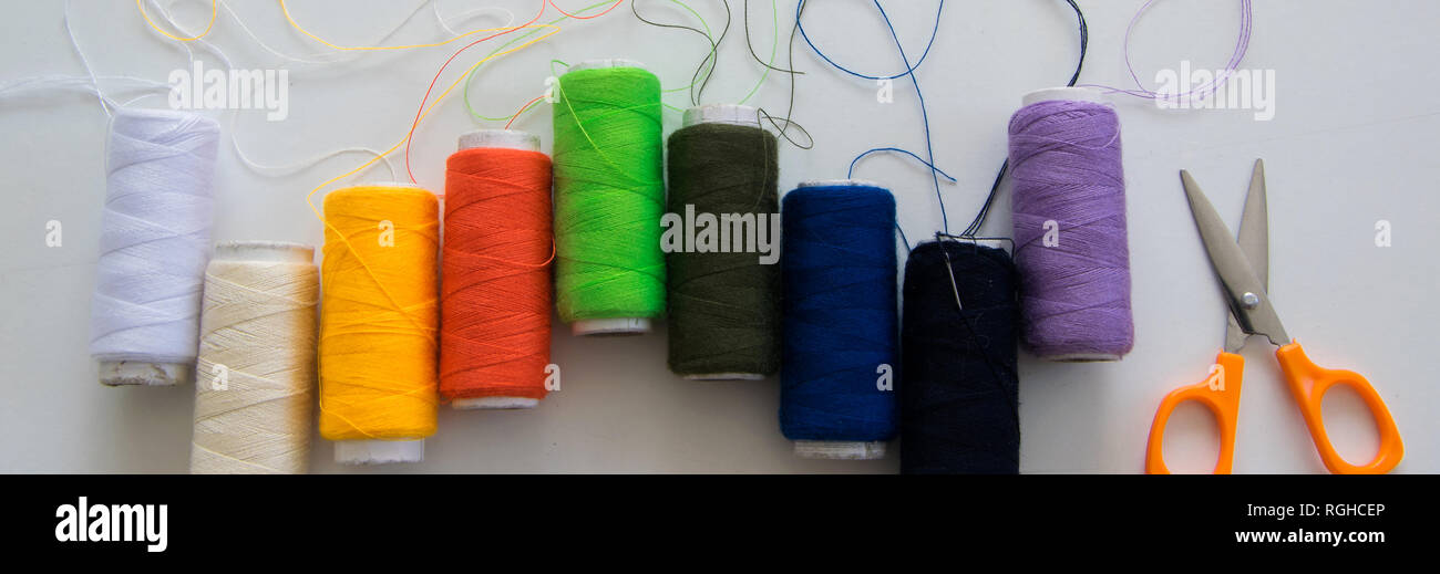 Top view of colorful sewing threads and a scissors on white background ...