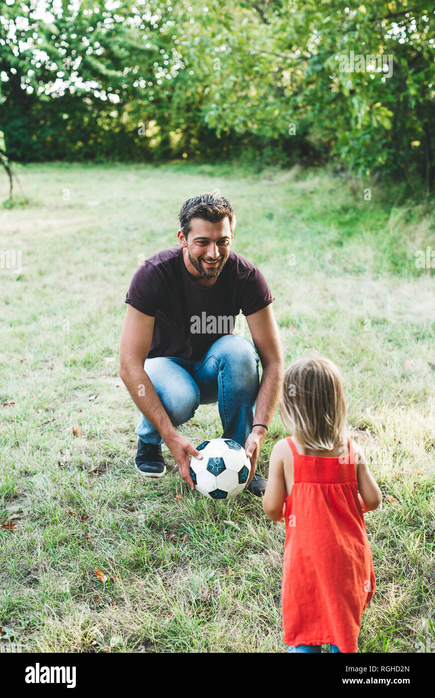 Happy father playing football with daughter on meadow Stock Photo - Alamy