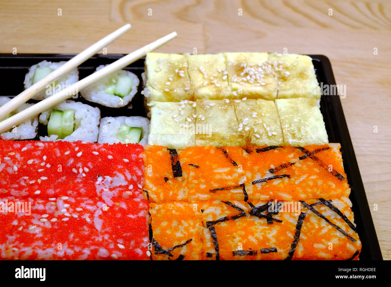 Sushi pieces on square tray on brown wooden table front view closeup ...