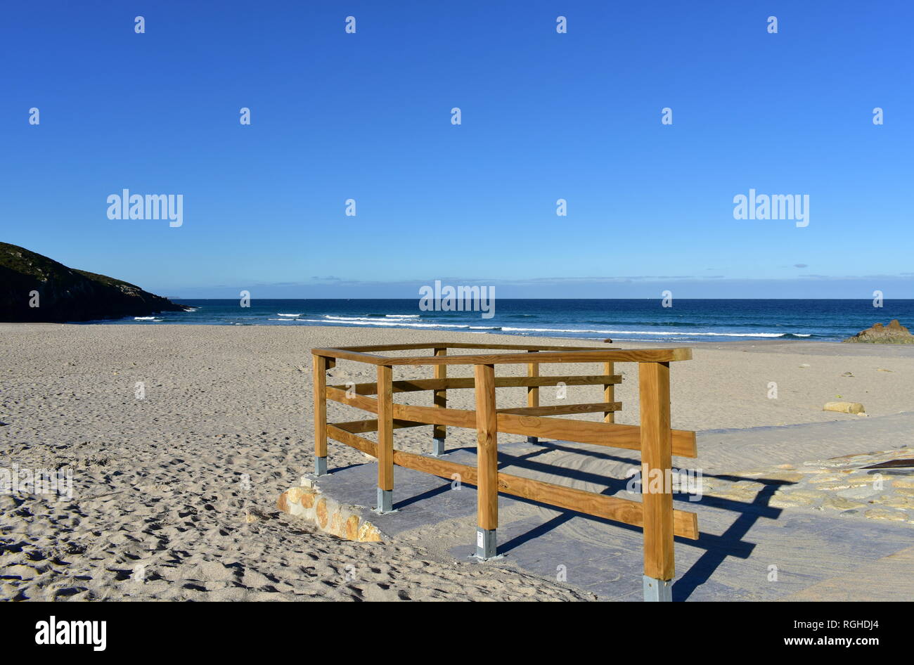 Beach with wooden handrail and morning light. Golden sand and blue sea ...
