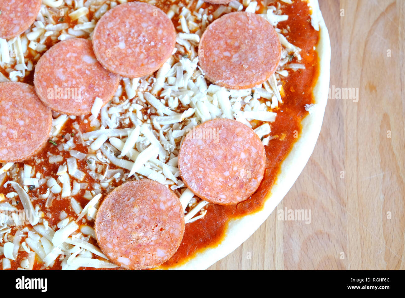 Still life with part of unready pizza with sausage on sandy brown ...