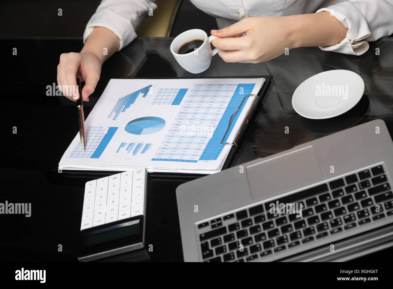 Businesswoman with coffee and pen points to graph Stock Photo - Alamy