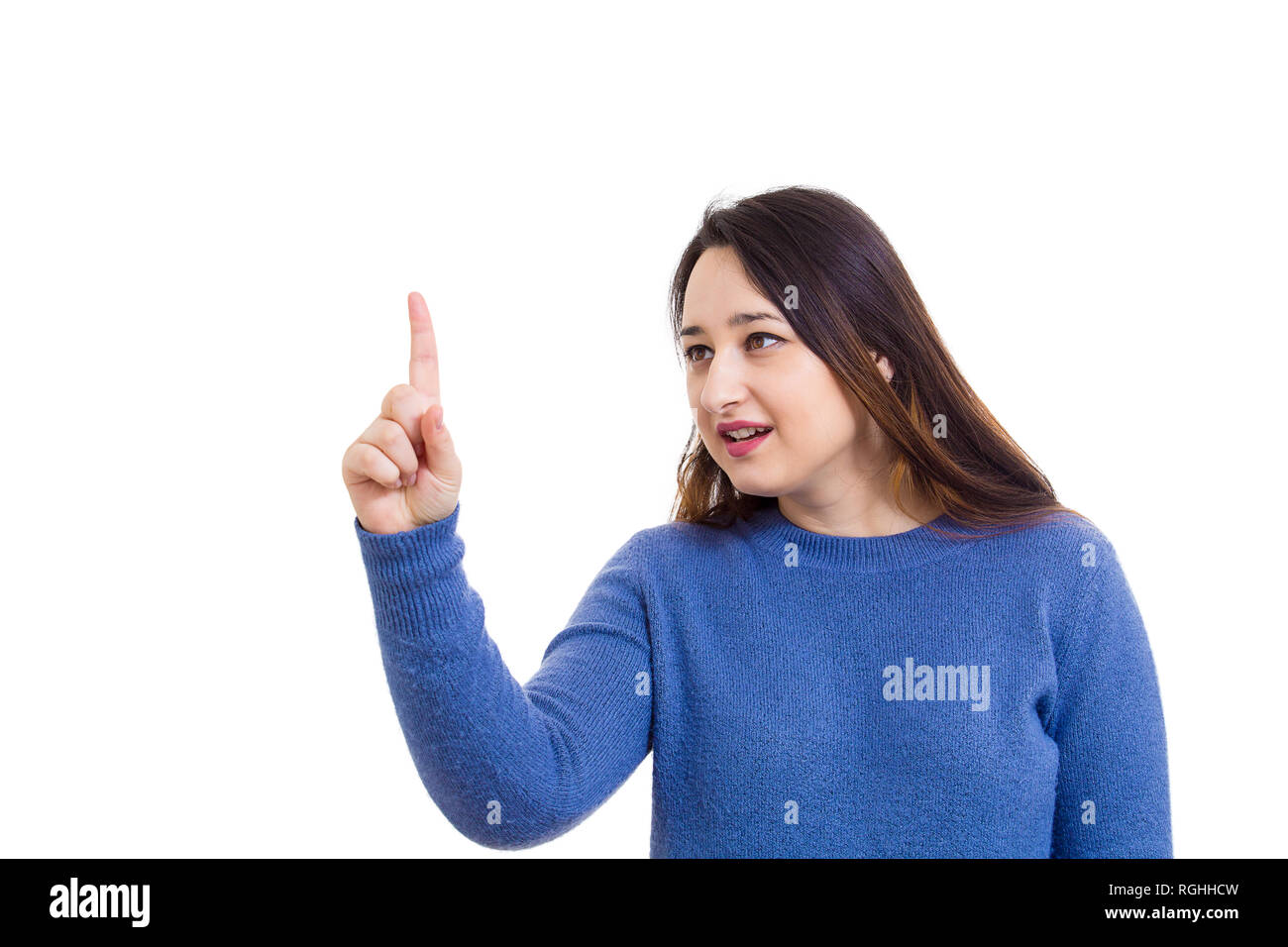 Attentive casual young woman pointing index finger like touching an ...