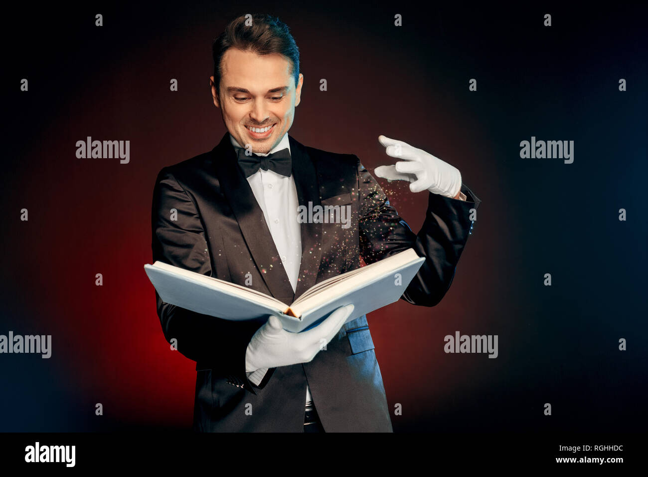Professional magician wearing suit nd gloves standing isolated on black ...