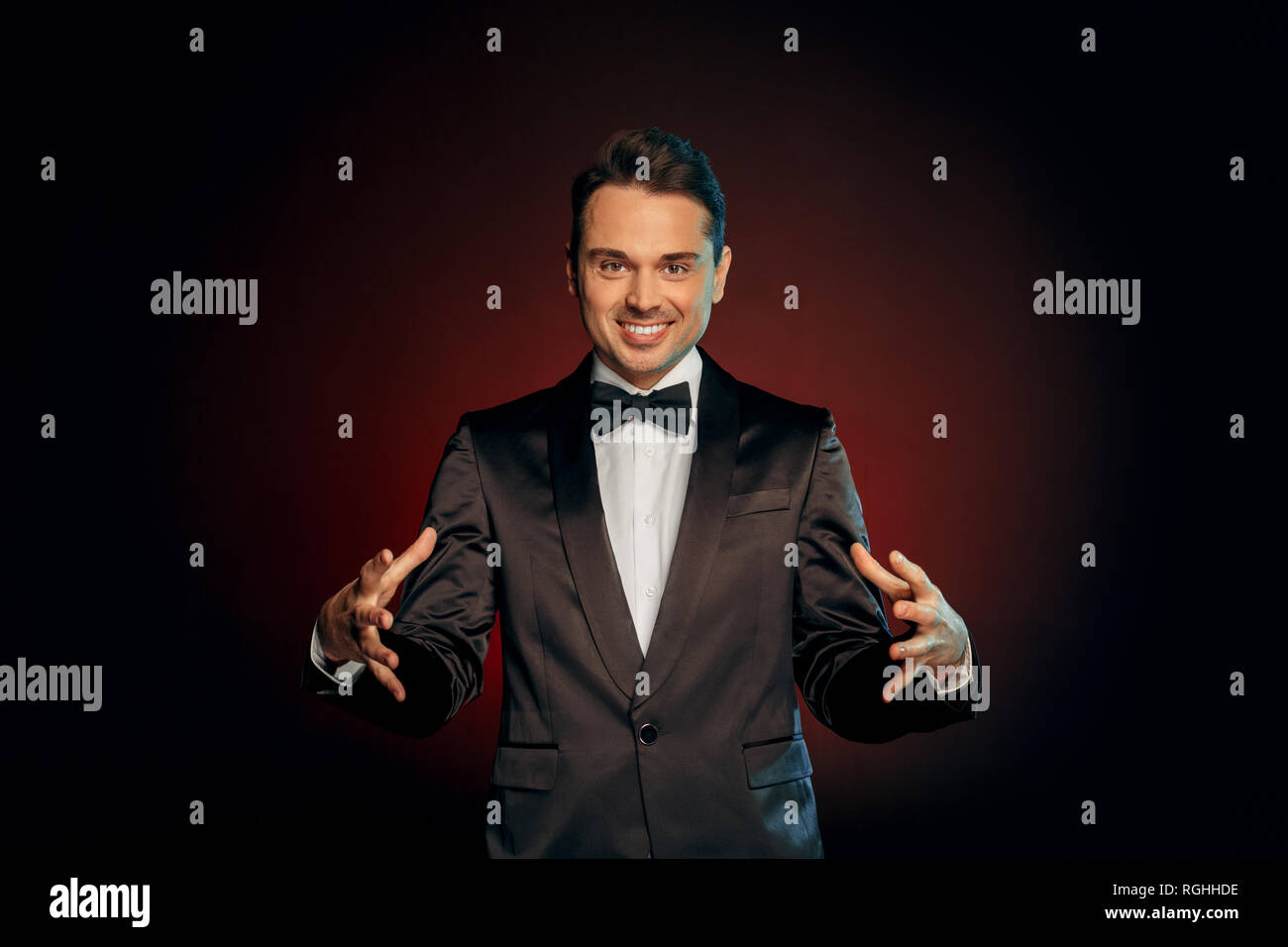 Professional showman wearing suit standing isolated on black and red ...