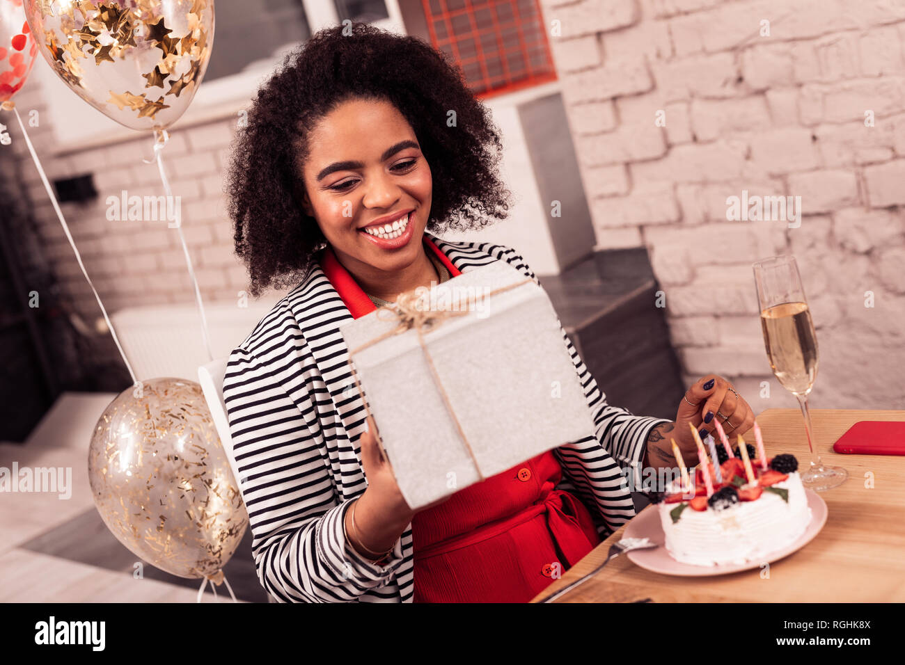 Delighted positive woman looking at the present Stock Photo - Alamy