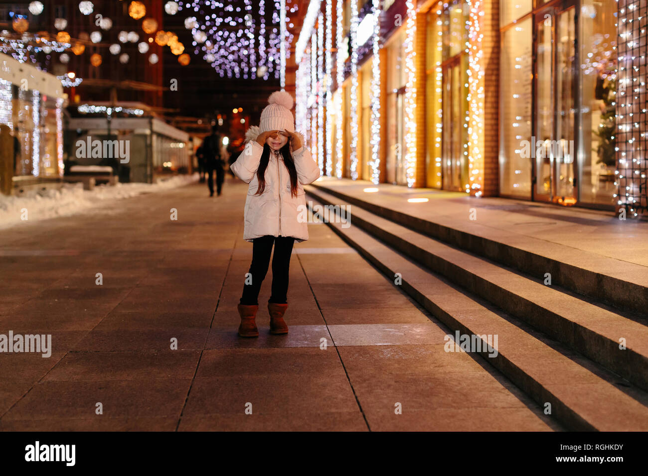 Cute scared lost little girl in a big city in the evening in winter ...