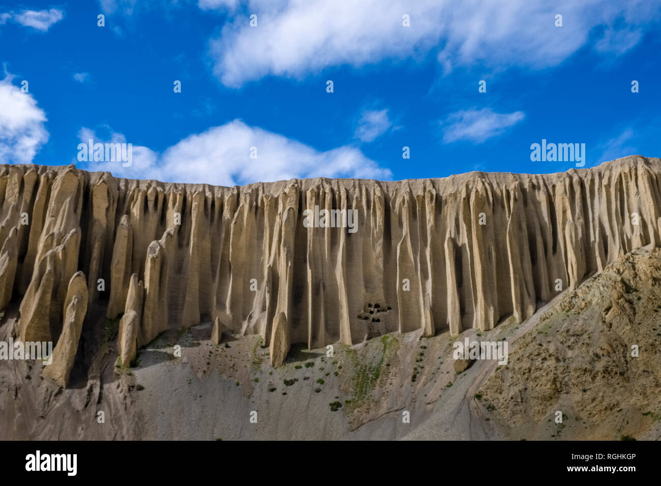 Vertically formed rock cliff with man made caves Stock Photo - Alamy