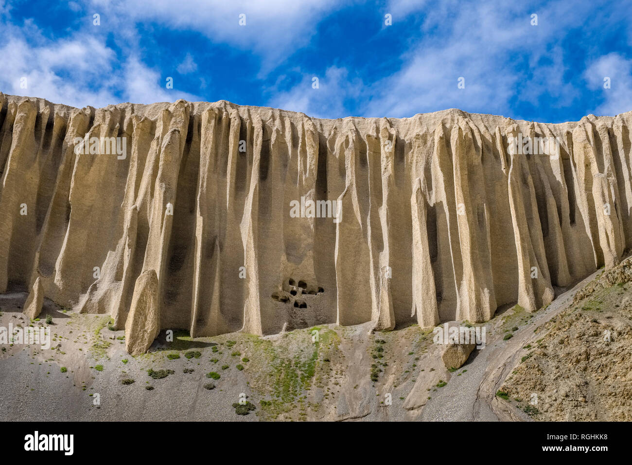 Vertically formed rock cliff with man made caves Stock Photo - Alamy