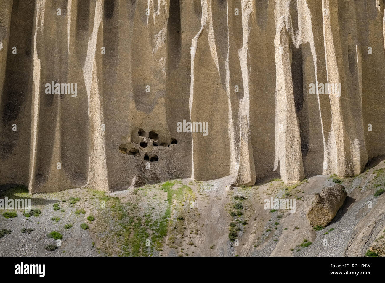 Vertically formed rock cliff with man made caves Stock Photo - Alamy