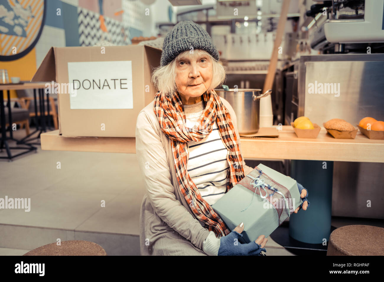 Nice homeless woman holding a gift box Stock Photo - Alamy