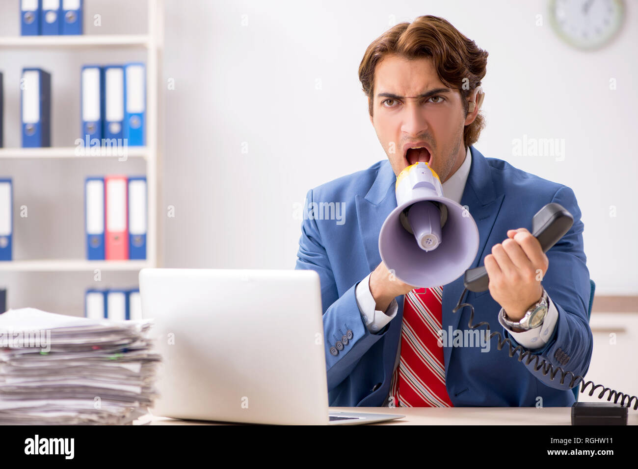 Deaf employee using hearing aid in office Stock Photo - Alamy