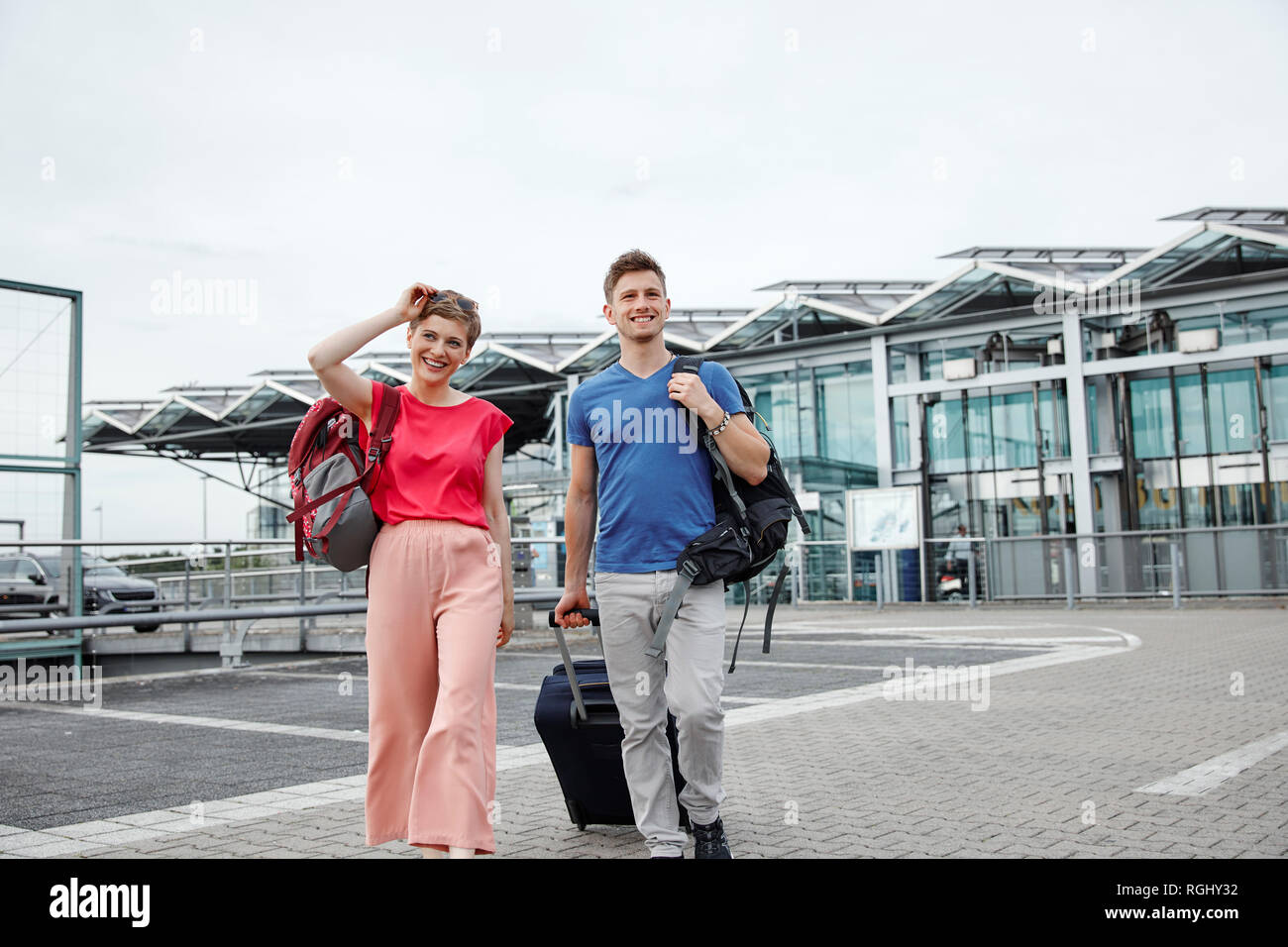 Smiling couple walking outside airport Stock Photo - Alamy