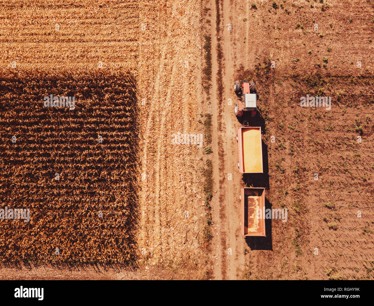 Aerial view of agricultural tractor with cargo carts in field loaded ...
