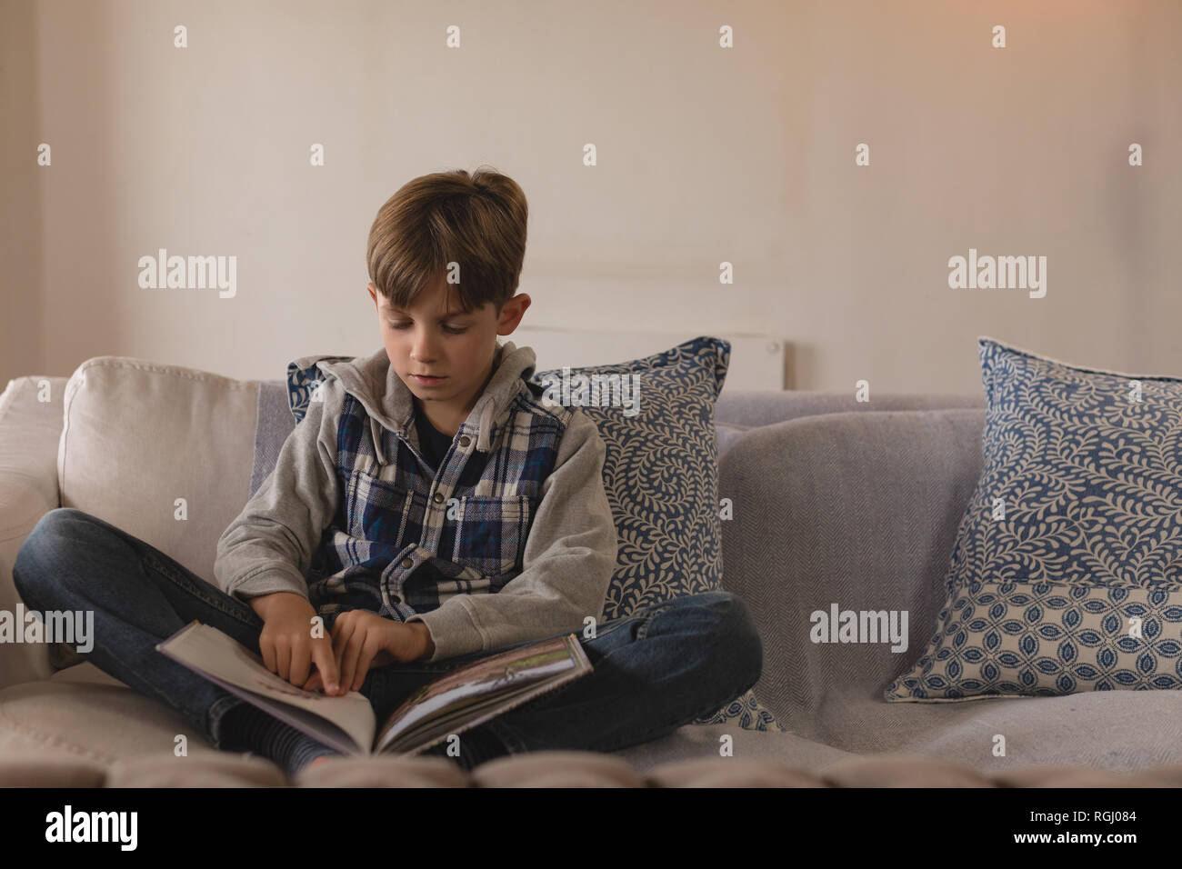 Boy reading a story book in living room Stock Photo - Alamy