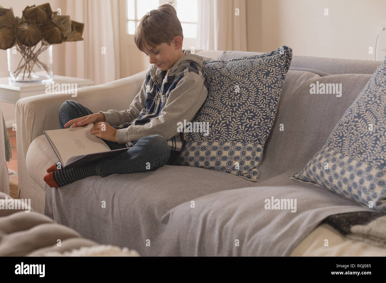 Boy reading a story book in living room Stock Photo - Alamy