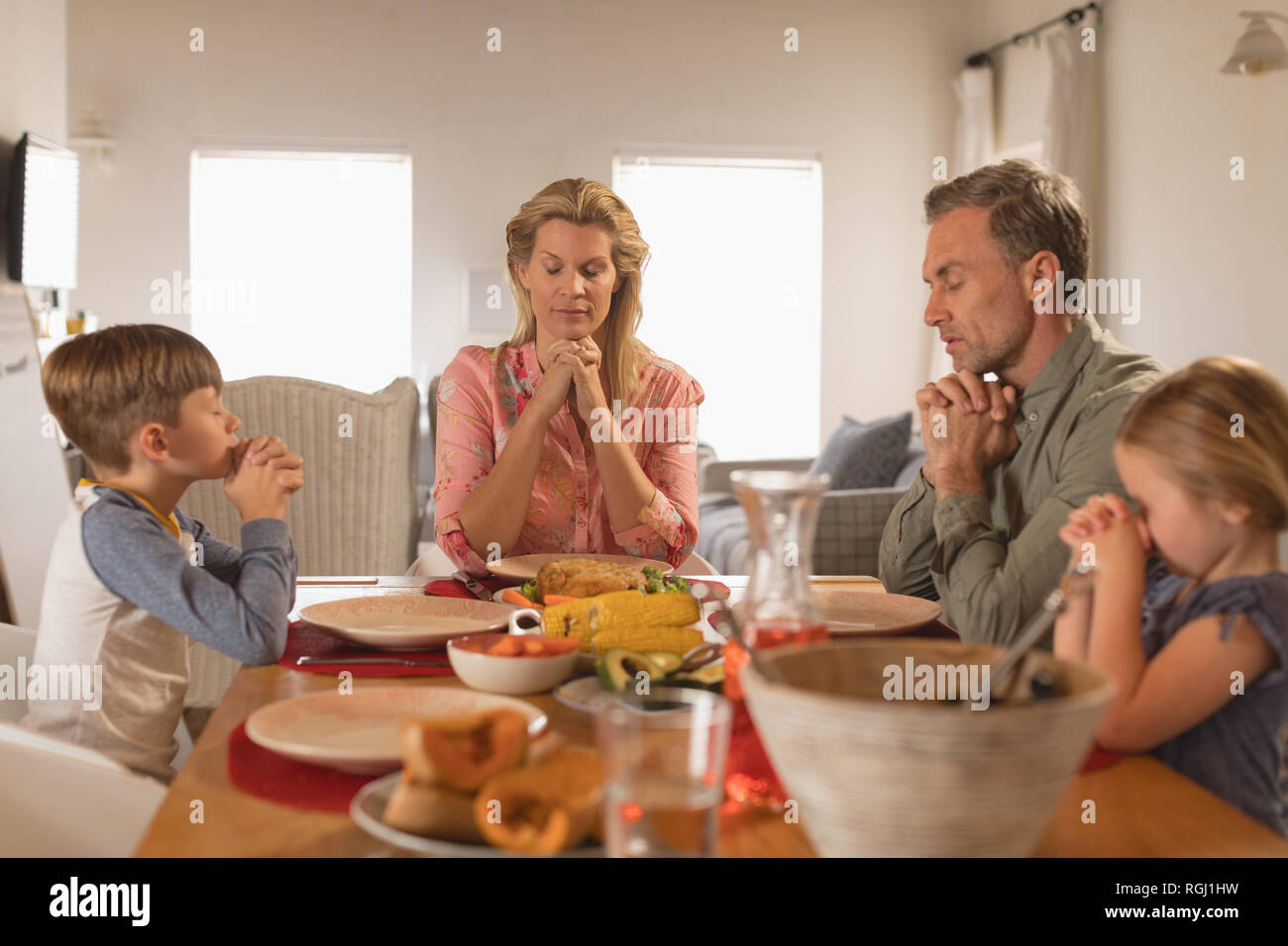 Surface level of a family praying before having food on dining table at ...
