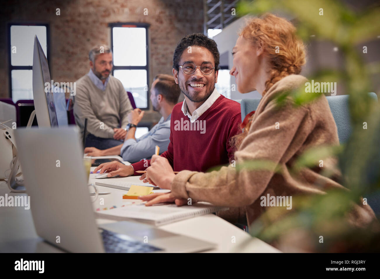 Colleague helping young man at work Stock Photo - Alamy