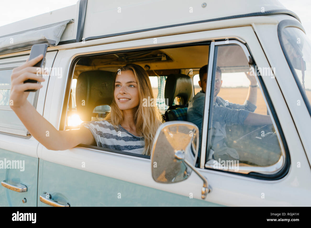 Smiling woman taking a selfie in a camper van with man driving Stock ...