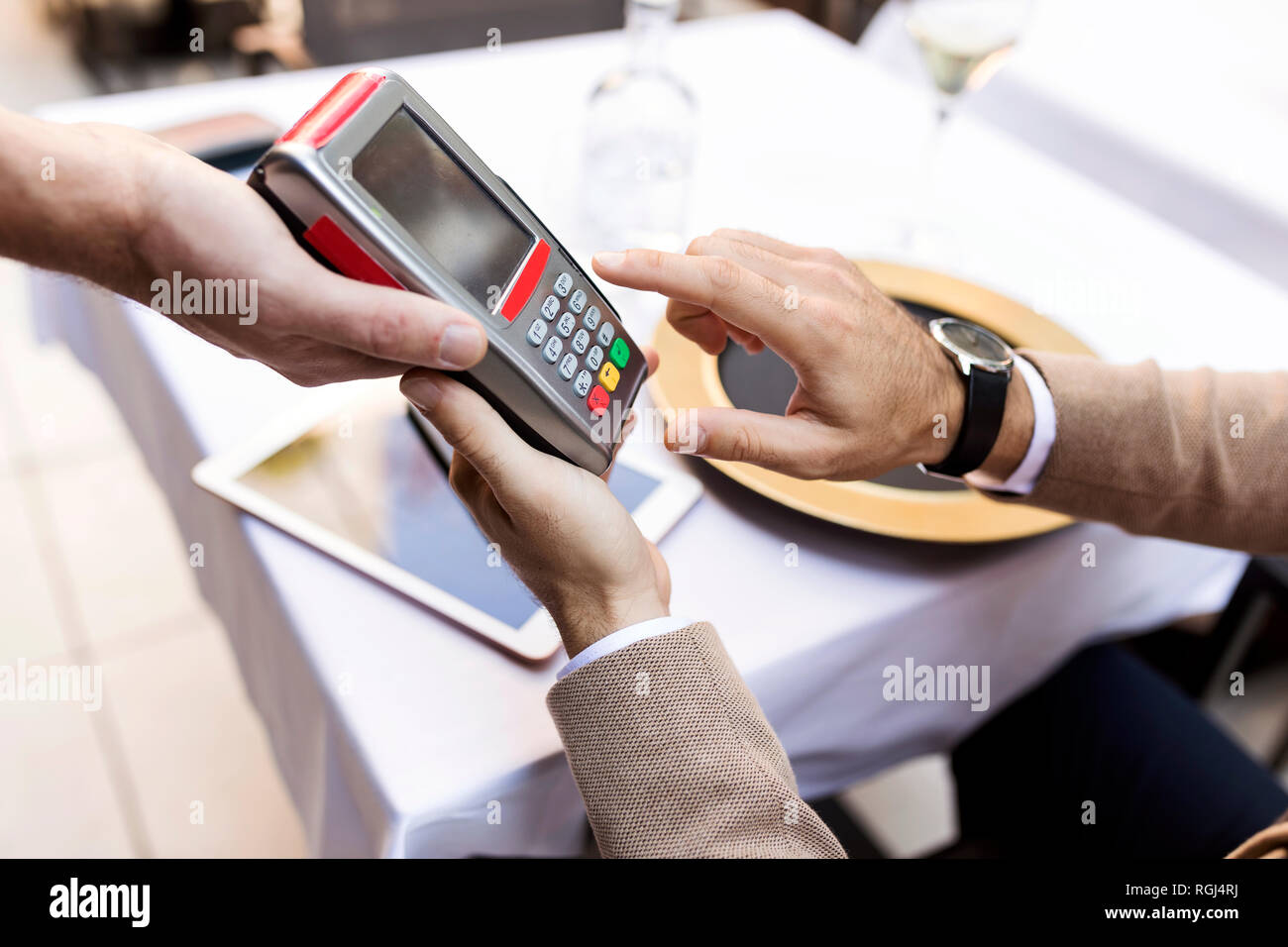 Man entering pin into card reader in a restaurant Stock Photo - Alamy