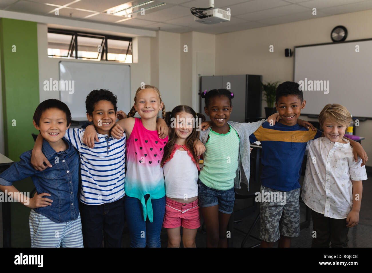 Happy school kids standing and looking at camera in classroom of ...