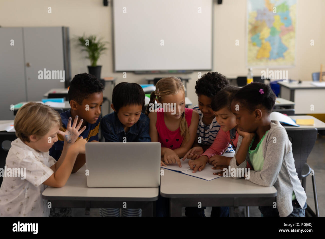 Front view of a group of school kids studying together in classroom of ...