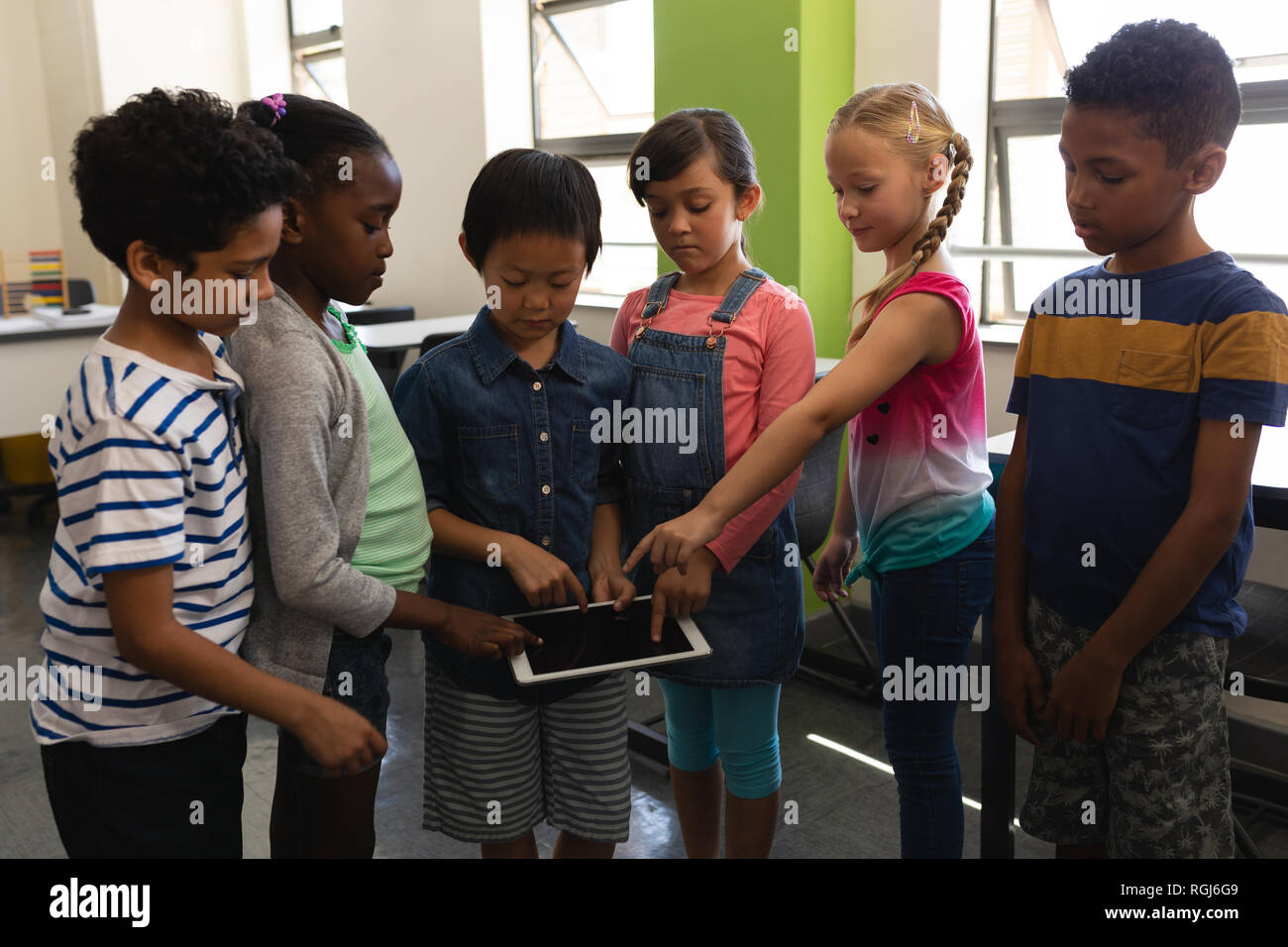 Group of school kids studying together on digital tablet in classroom ...