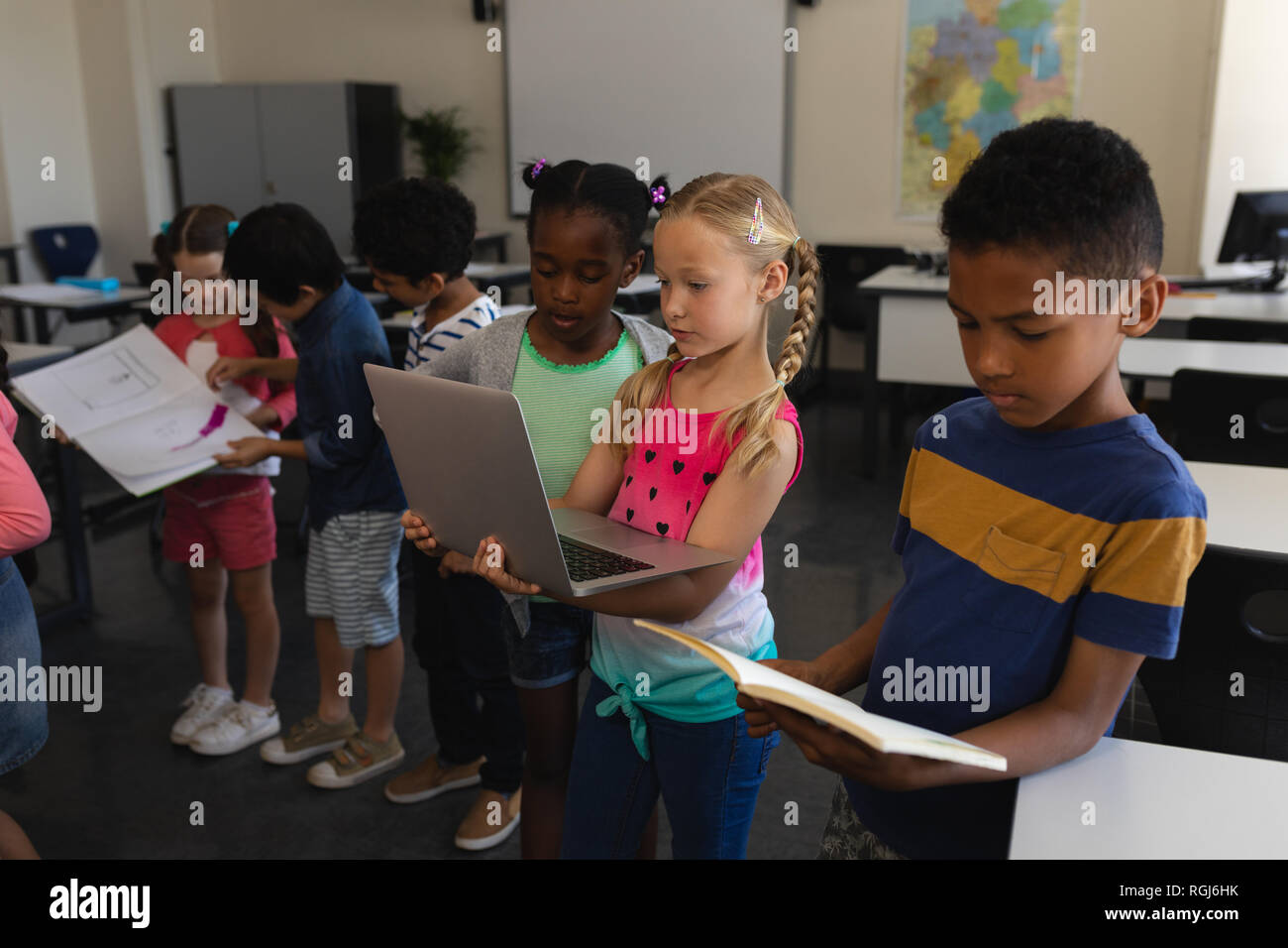 Side view of group of school kids studying together in classroom of ...