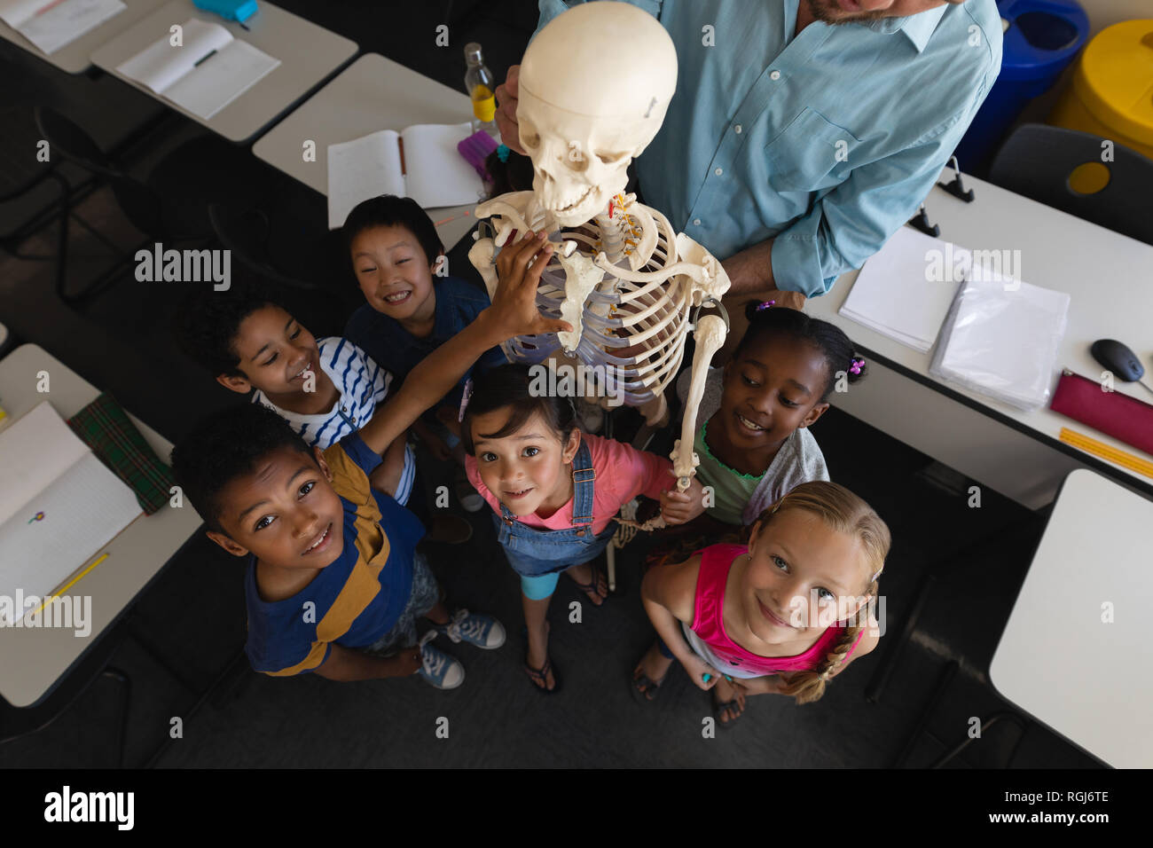 Overhead of schoolkids looking at camera in classroom of elementary ...