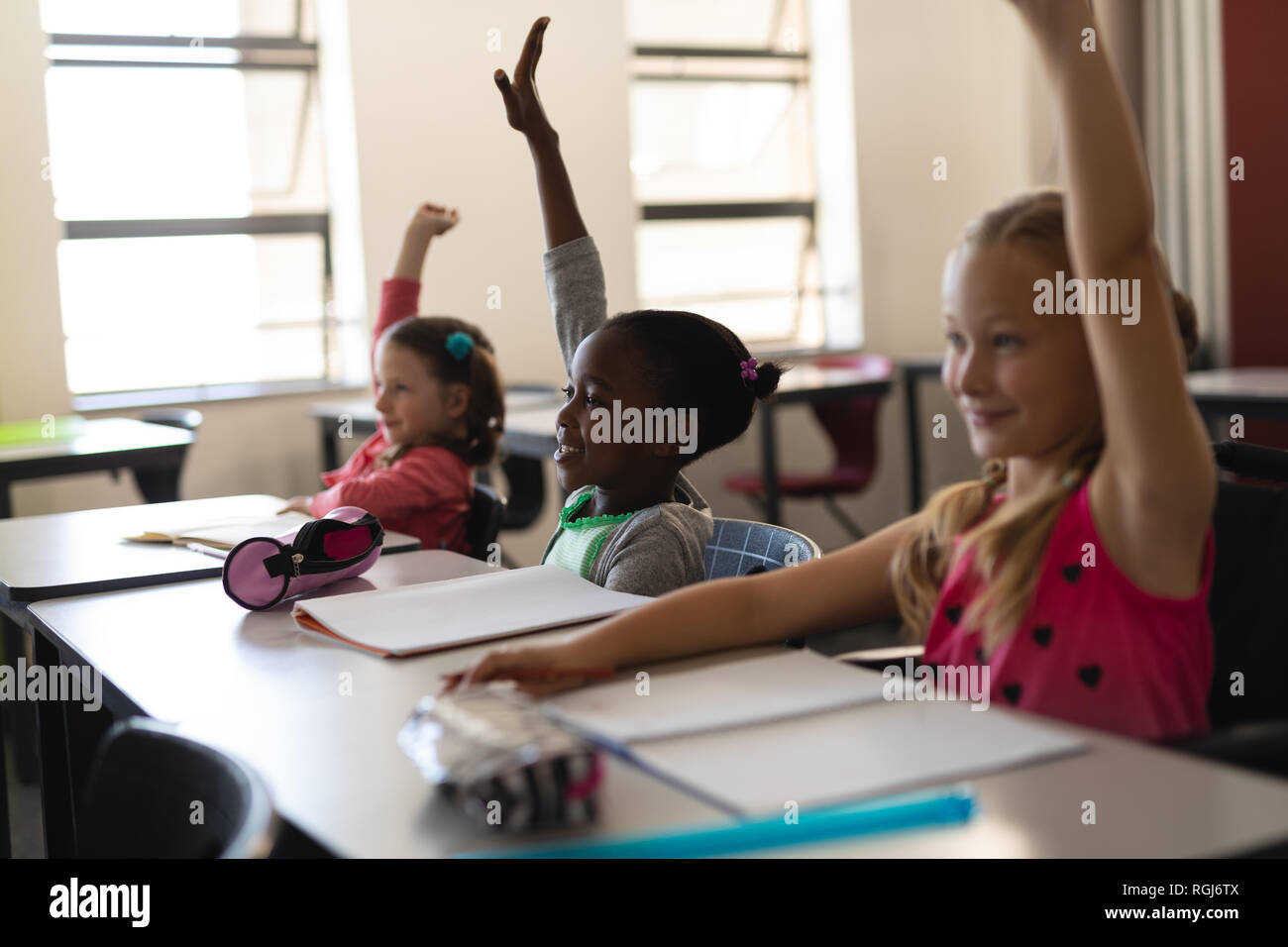 Schoolgirls raising hand in classroom of elementary school Stock Photo ...