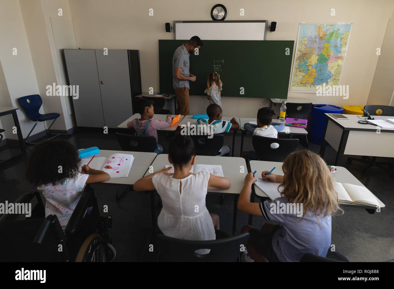 Rear view of schoolkids studying in classroom of elementary school ...