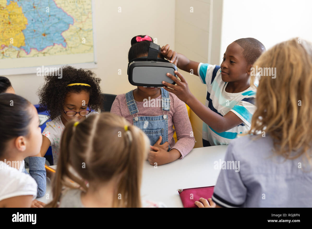 Front view schoolkids using virtual reality headset one of them help ...