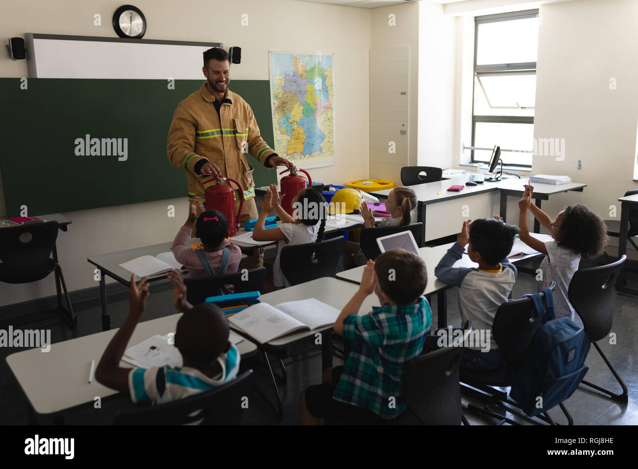 Front view of a schoolkids applauding while male Caucasian firefighter ...