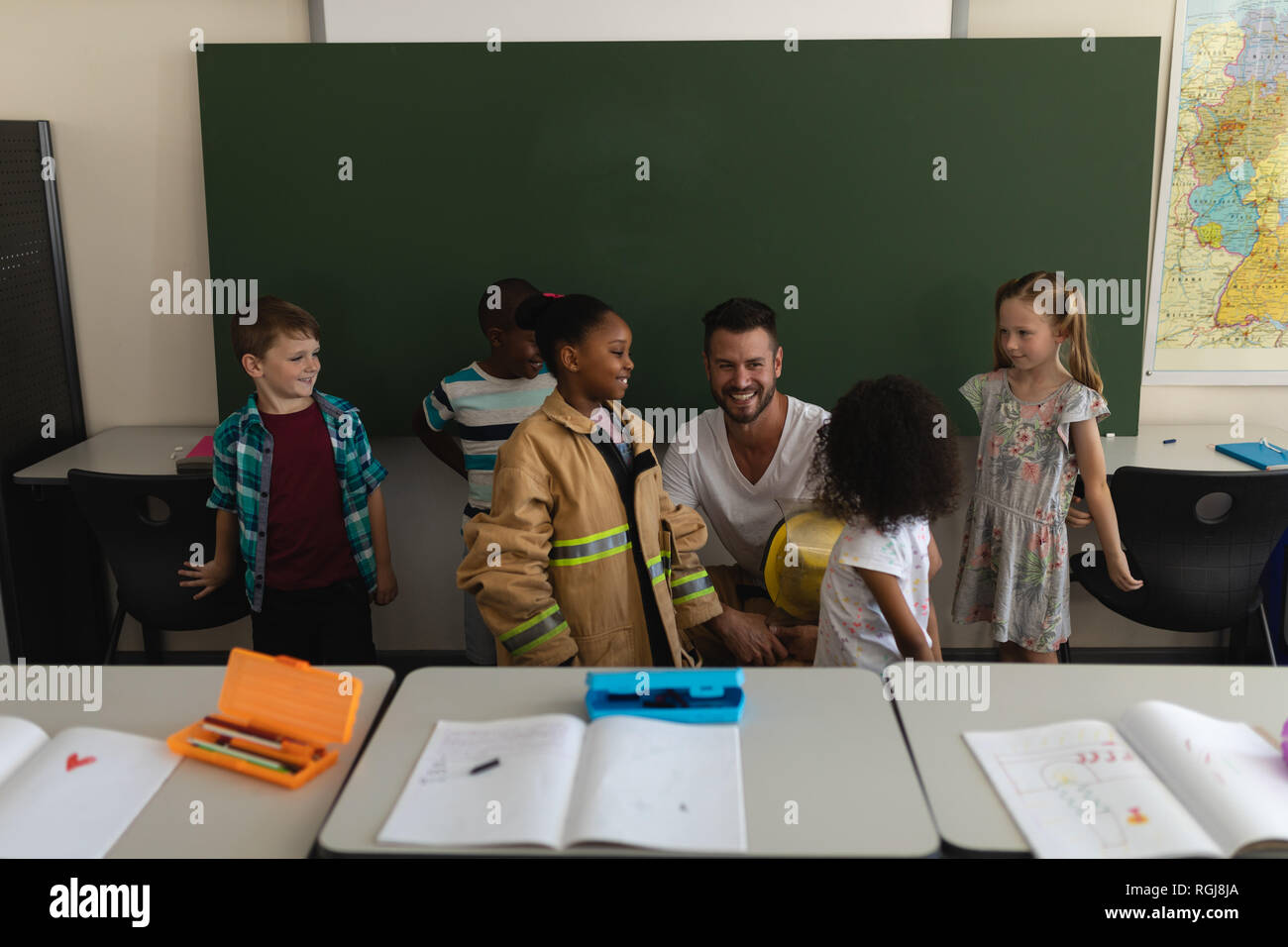 Front view of male firefighter teaching schoolkids about fire safety in ...