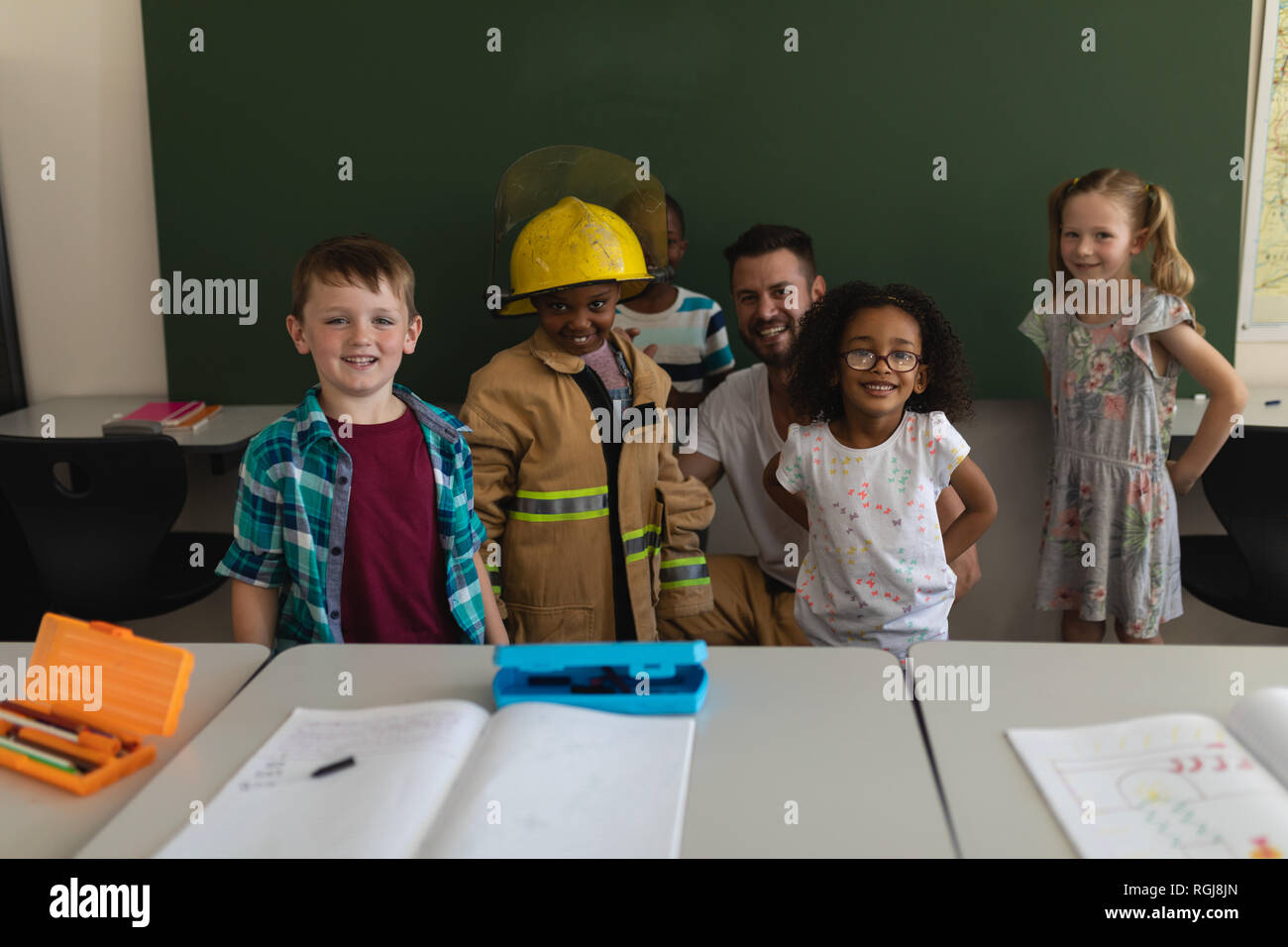 Front view happy male firefighter with schoolkids looking at camera and ...