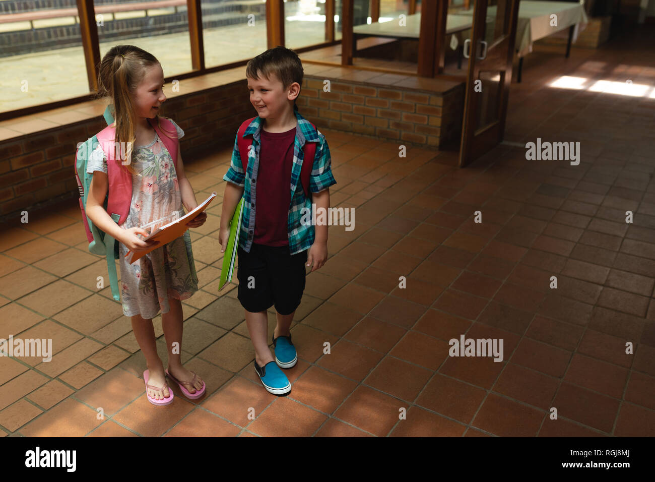 Schoolkids talking with each other in corridor of elementary school ...