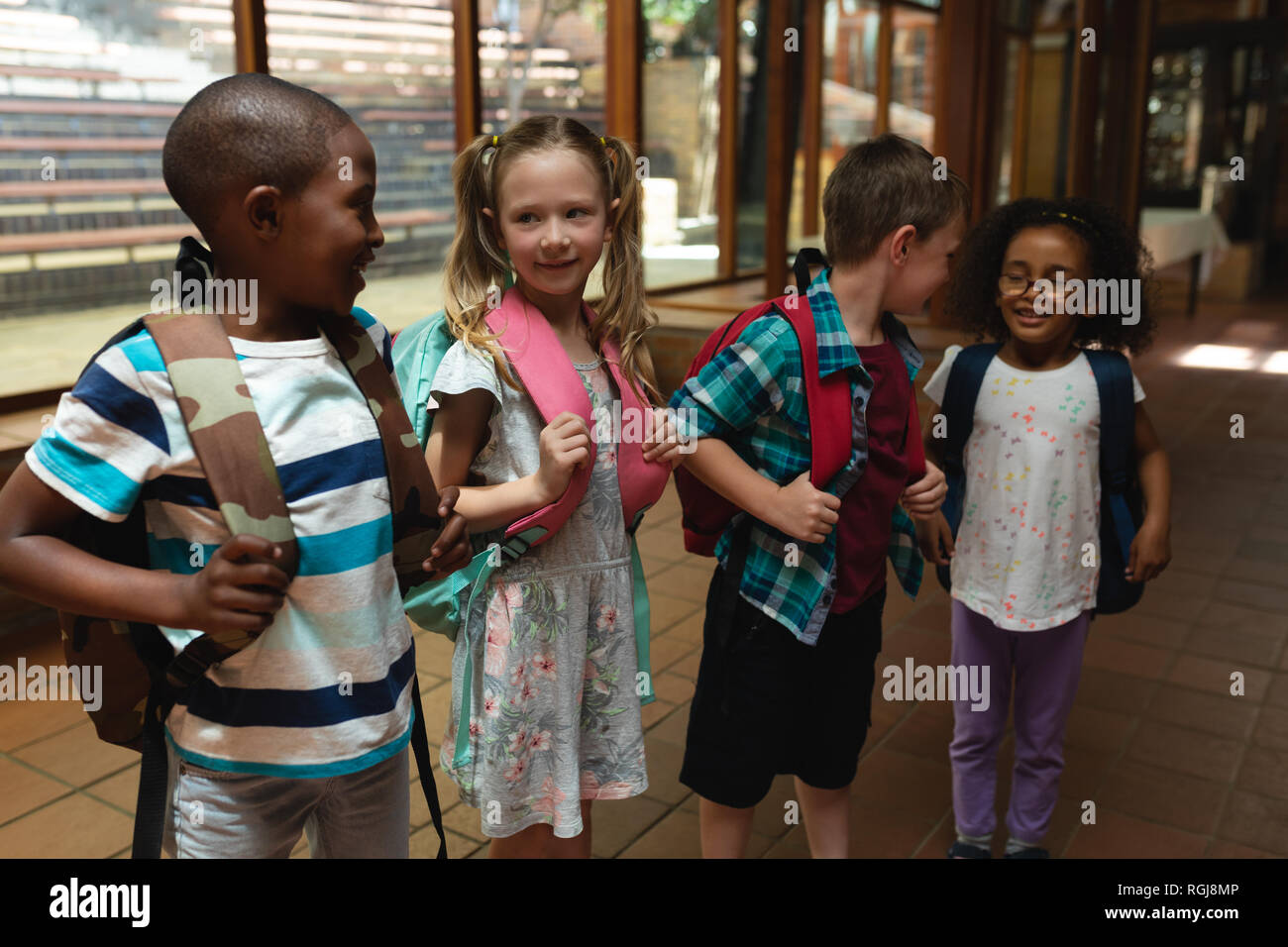 Schoolkids talking with each other in corridor of elementary school ...