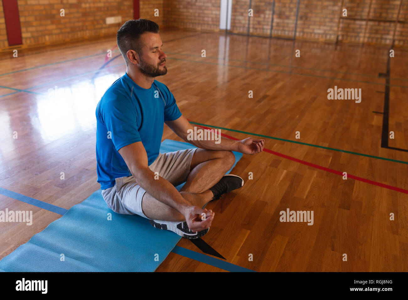 Yoga teacher doing yoga and meditating on a yoga mat in school Stock ...