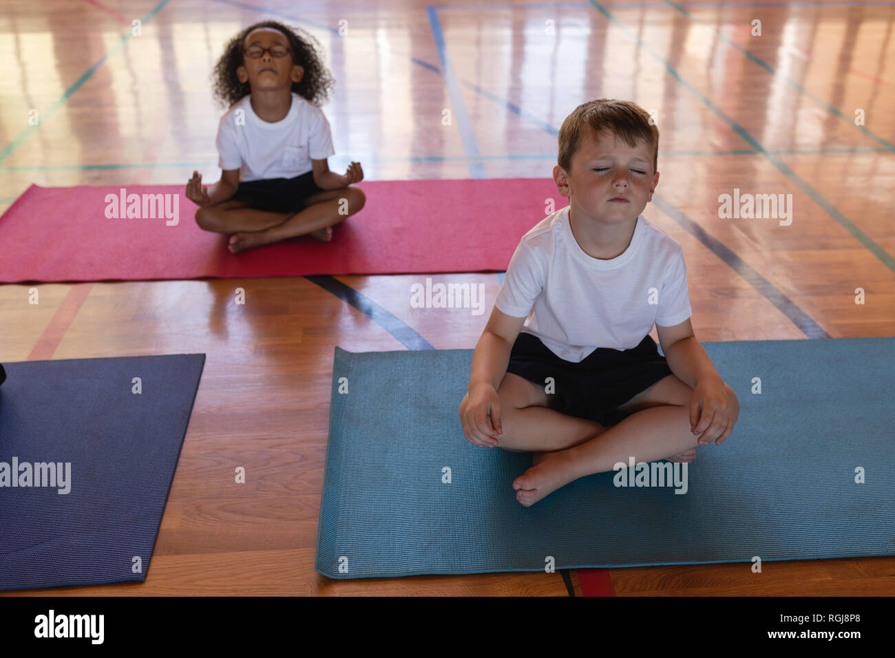 Schoolkids doing yoga and meditating on a yoga mat in school Stock ...