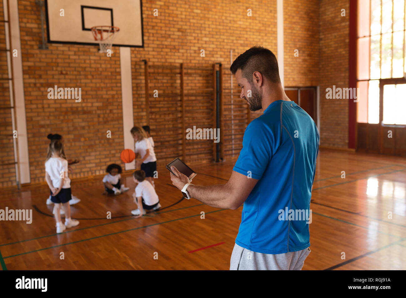 Side view of basketball coach using digital tablet at basketball court ...
