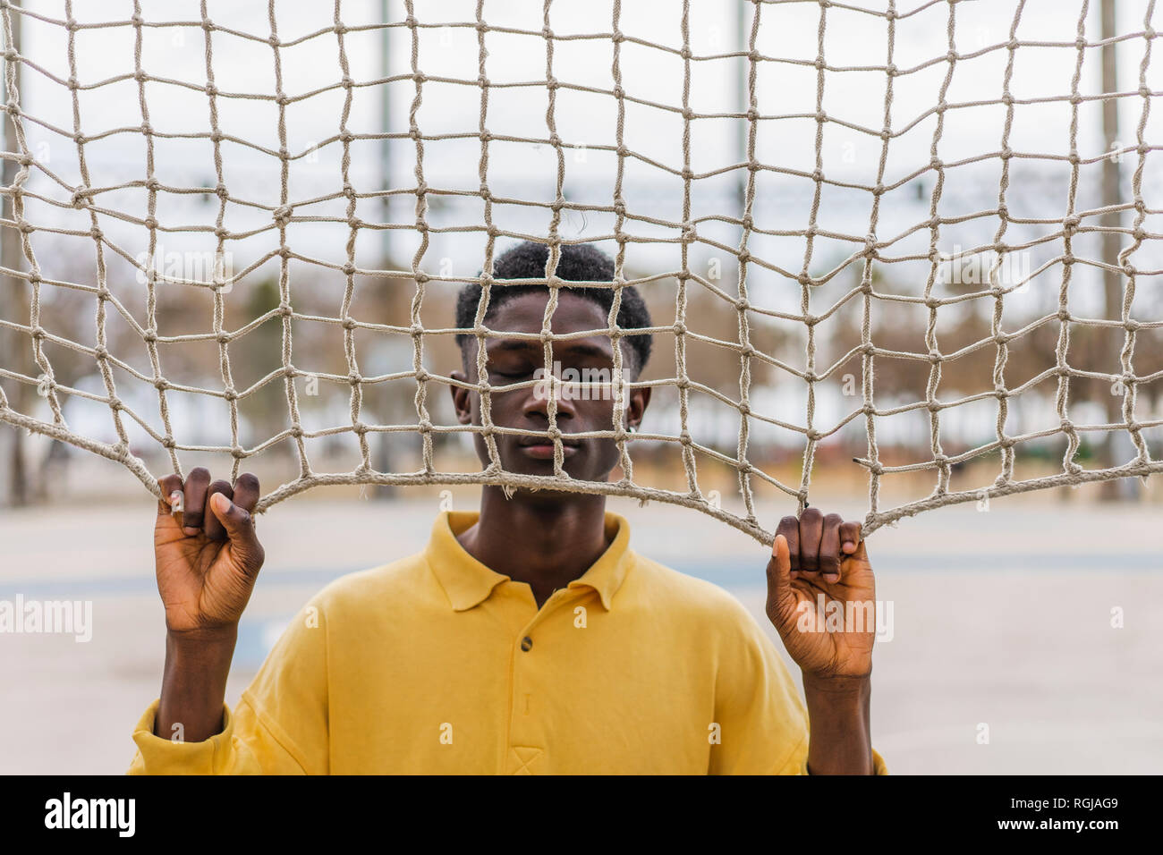 Young black man looking through volleyball net Stock Photo - Alamy