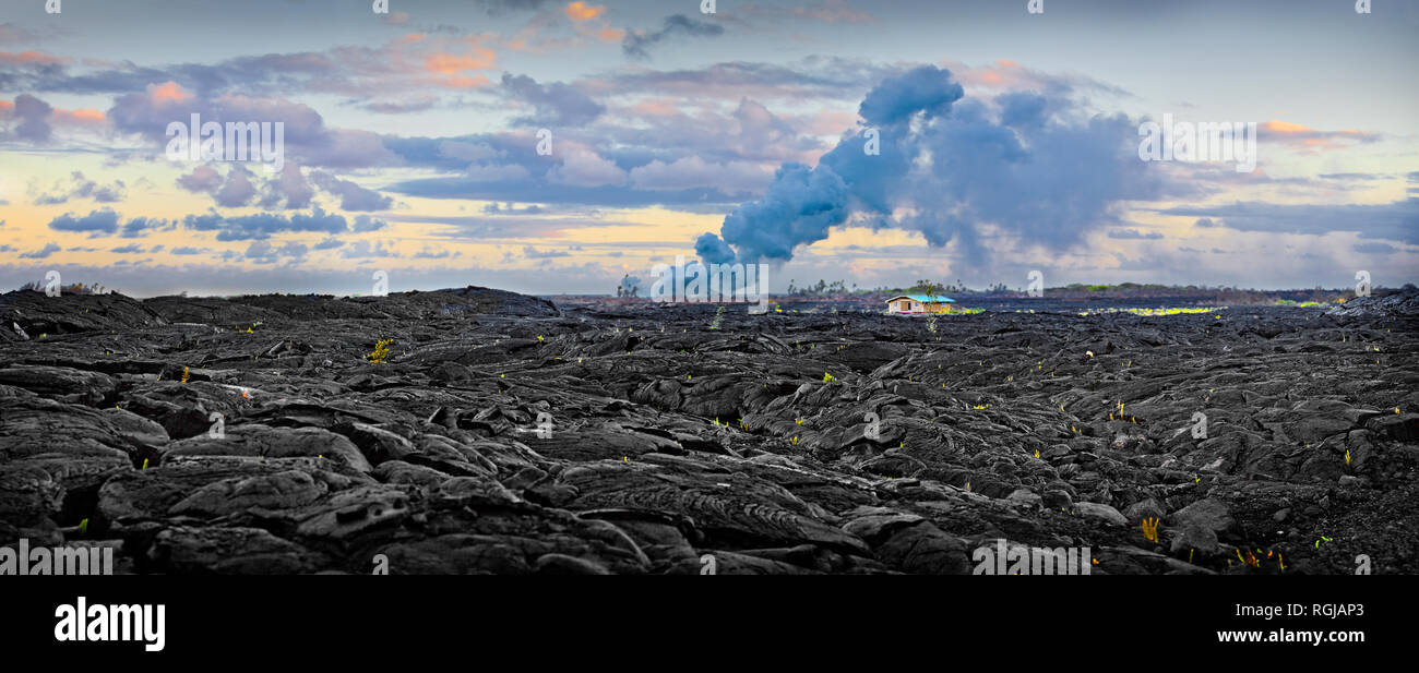 Volcanic rocky landscape with clouds and a house in the background ...