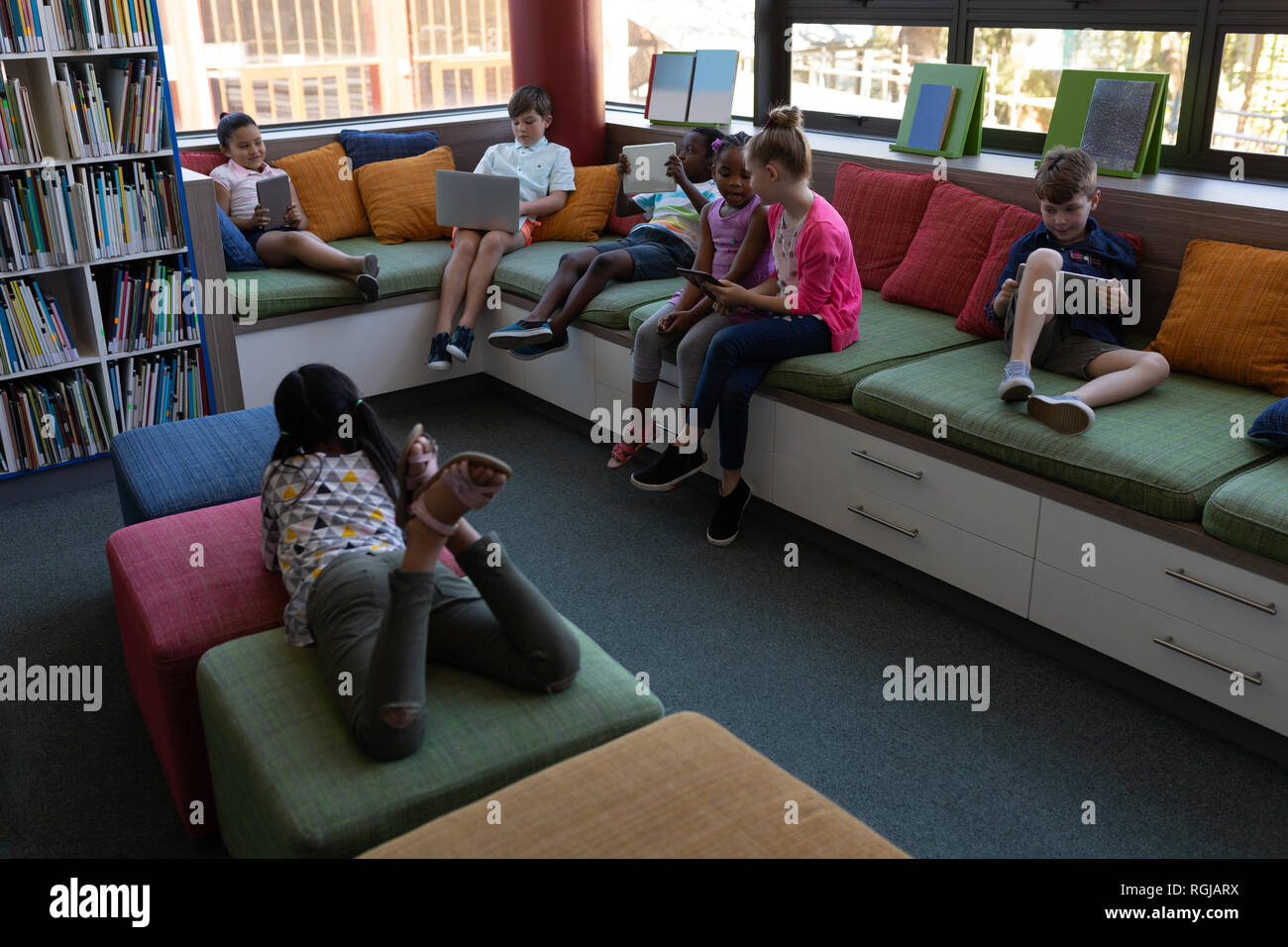 Front view of group of schoolkids studying while sitting on the couch ...