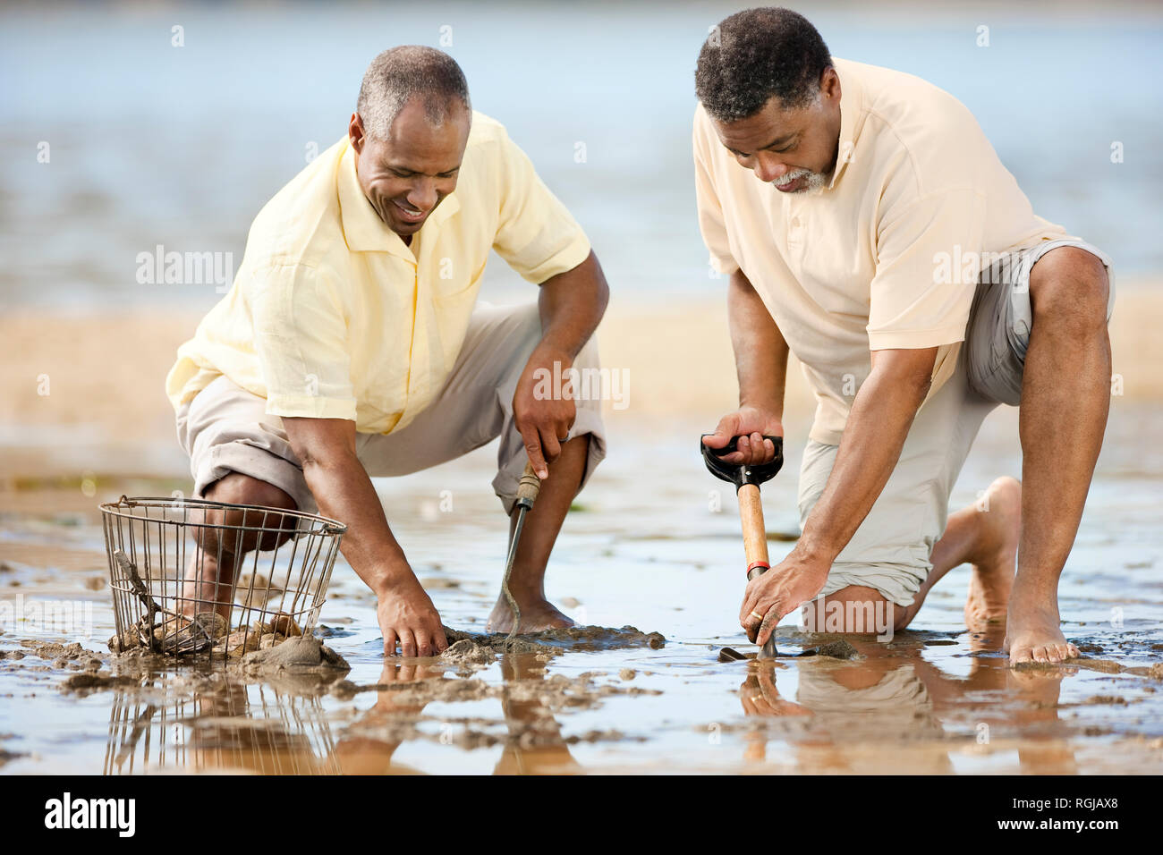 Father and son digging for shells on a beach Stock Photo - Alamy
