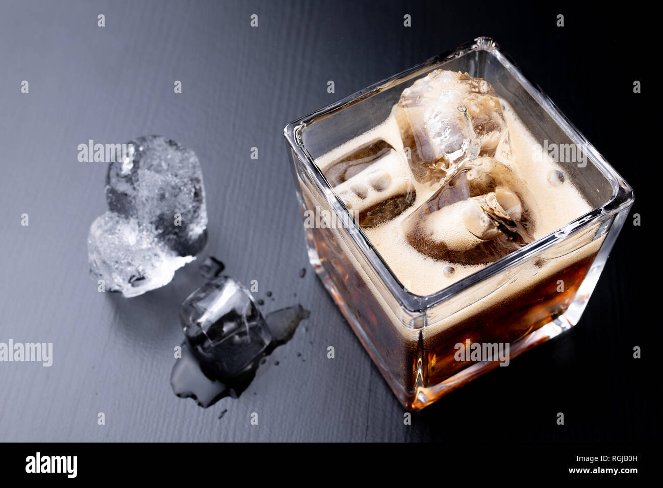A cold drink with ice on a dark table. A chilled drink in a glass ...
