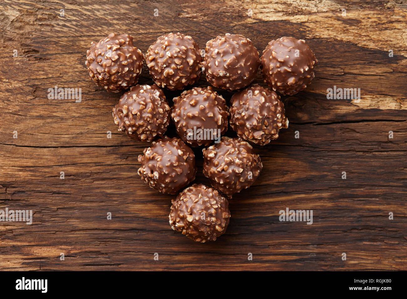 Chocolate truffle candies with hazelnuts shaped in triangle on wooden ...