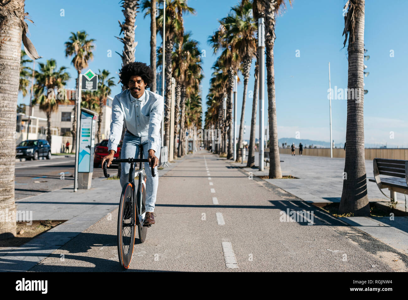 Mid adult man riding bicycle in the city, near the beach Stock Photo ...
