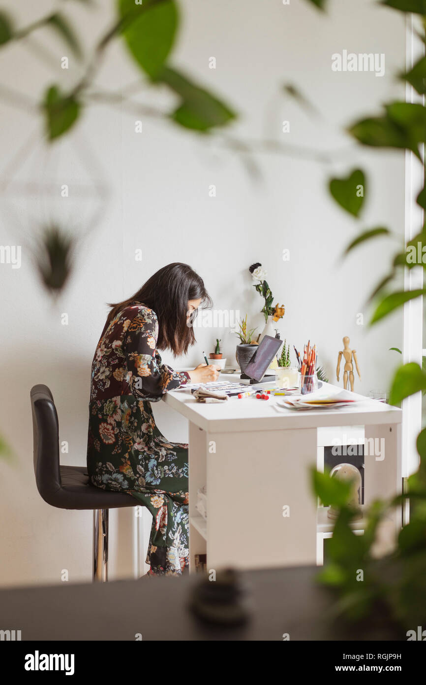 Illustrator painting at work desk in an atelier Stock Photo - Alamy